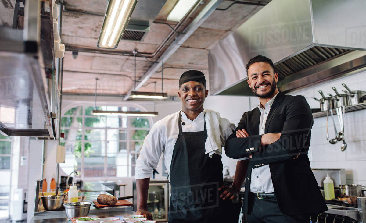 Portrait of restaurant owner with chef in kitchen. Businessman with ...