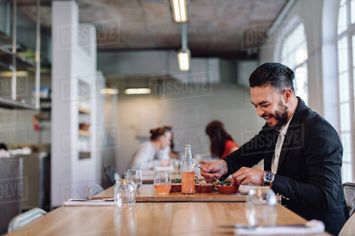 Happy businessman having food in restaurant. Smiling caucasian man ...