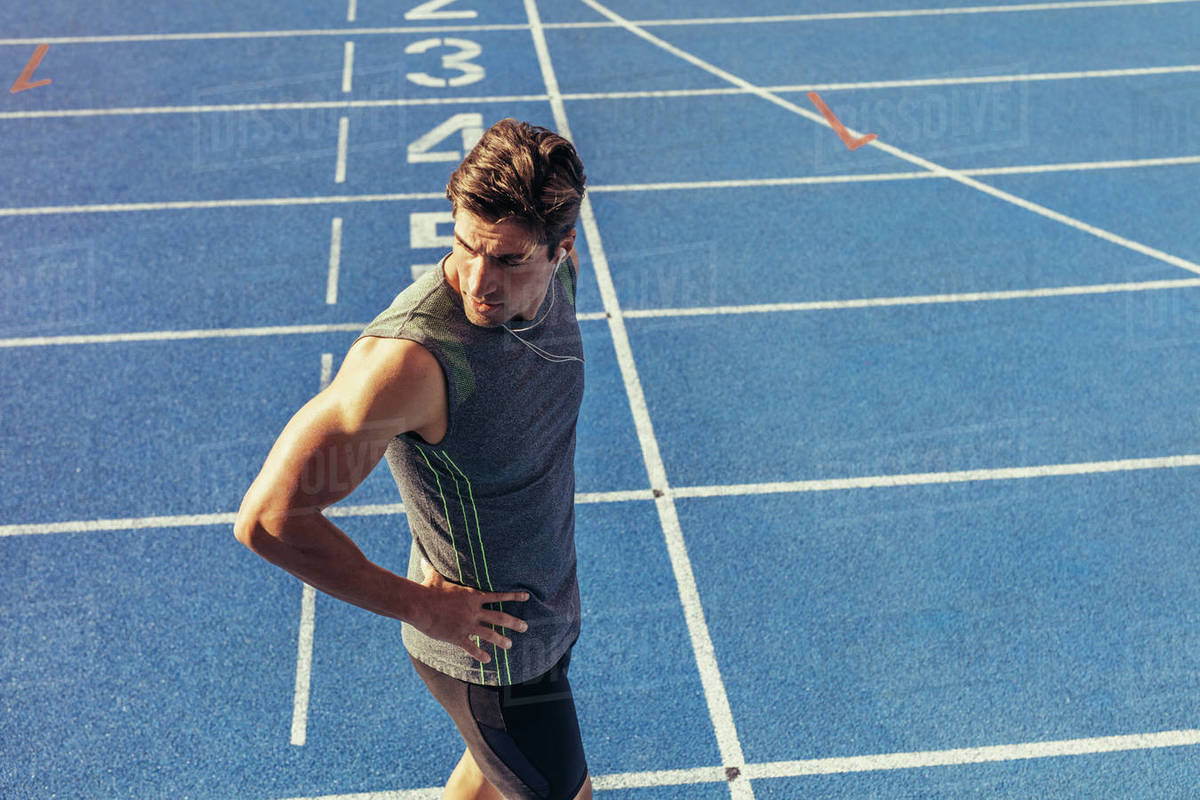 Athlete standing on a running track near the start line. Runner wearing ...