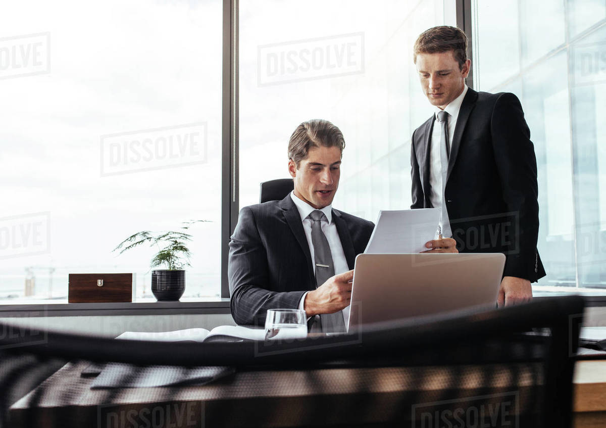 Business partners working together looking at contract papers. Two ...