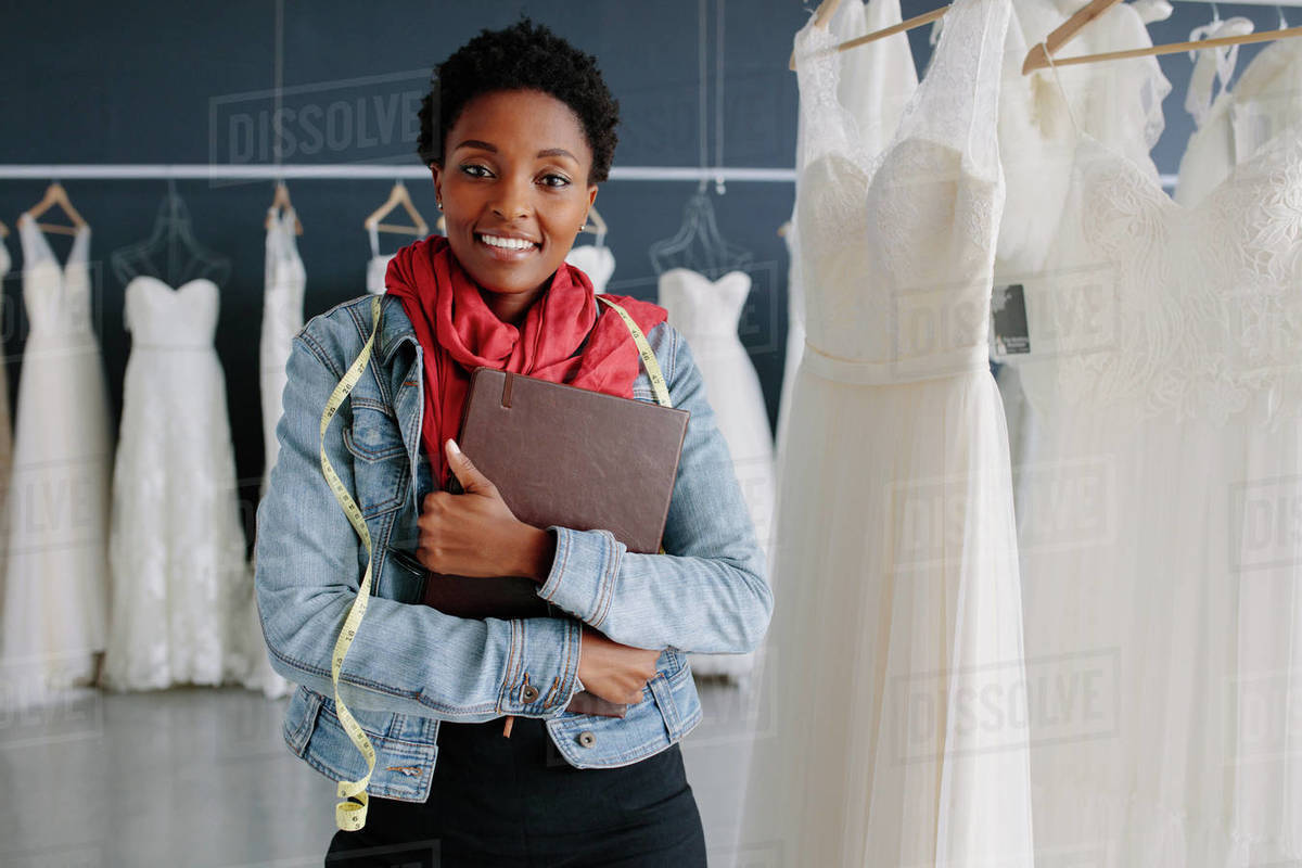 Portrait of wedding dress store owner with a diary. Woman dressmaker in ...