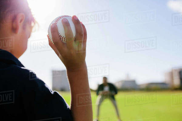 Rear view close up of a boy throwing baseball at a man in a ground. Boy ...