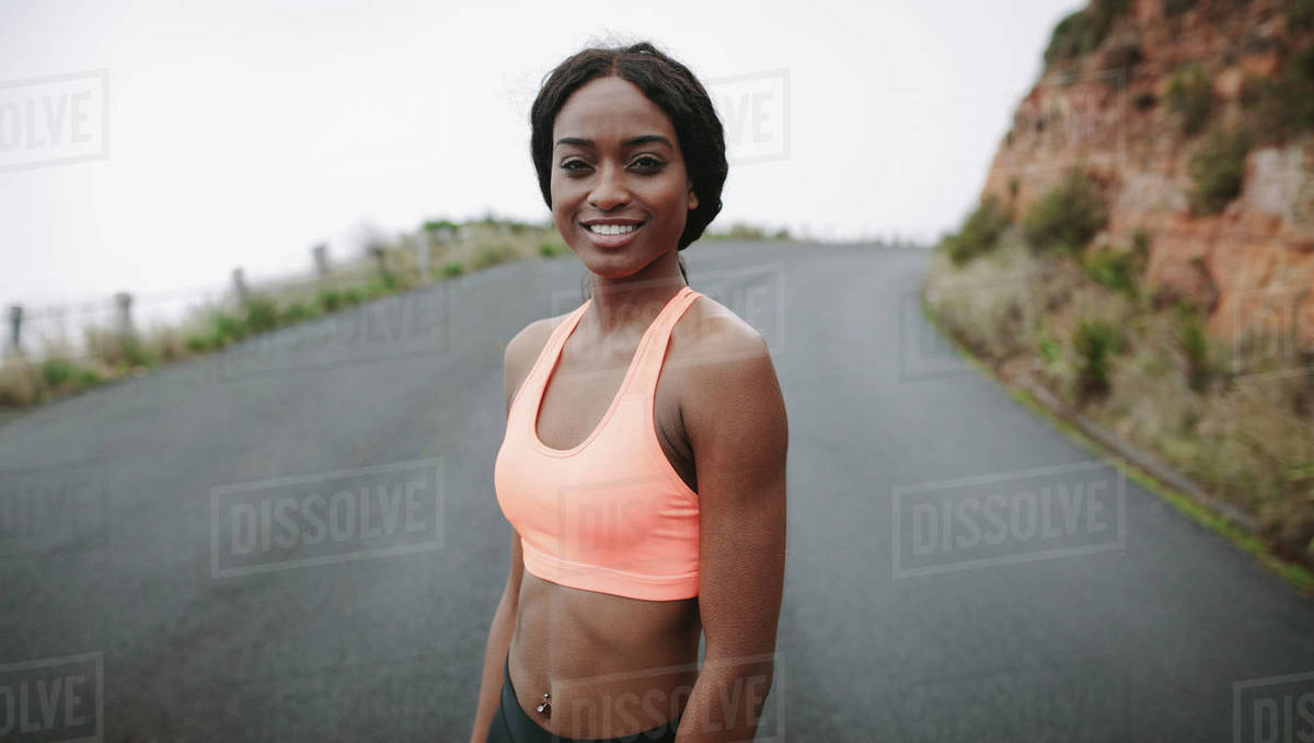 Closeup of woman athlete standing on empty road. Runner posing during ...