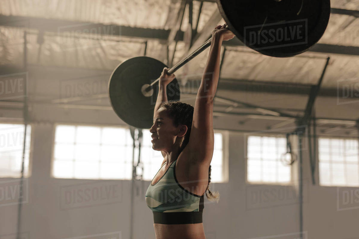 Strong woman with barbell overhead doing exercise. Fit female athlete ...