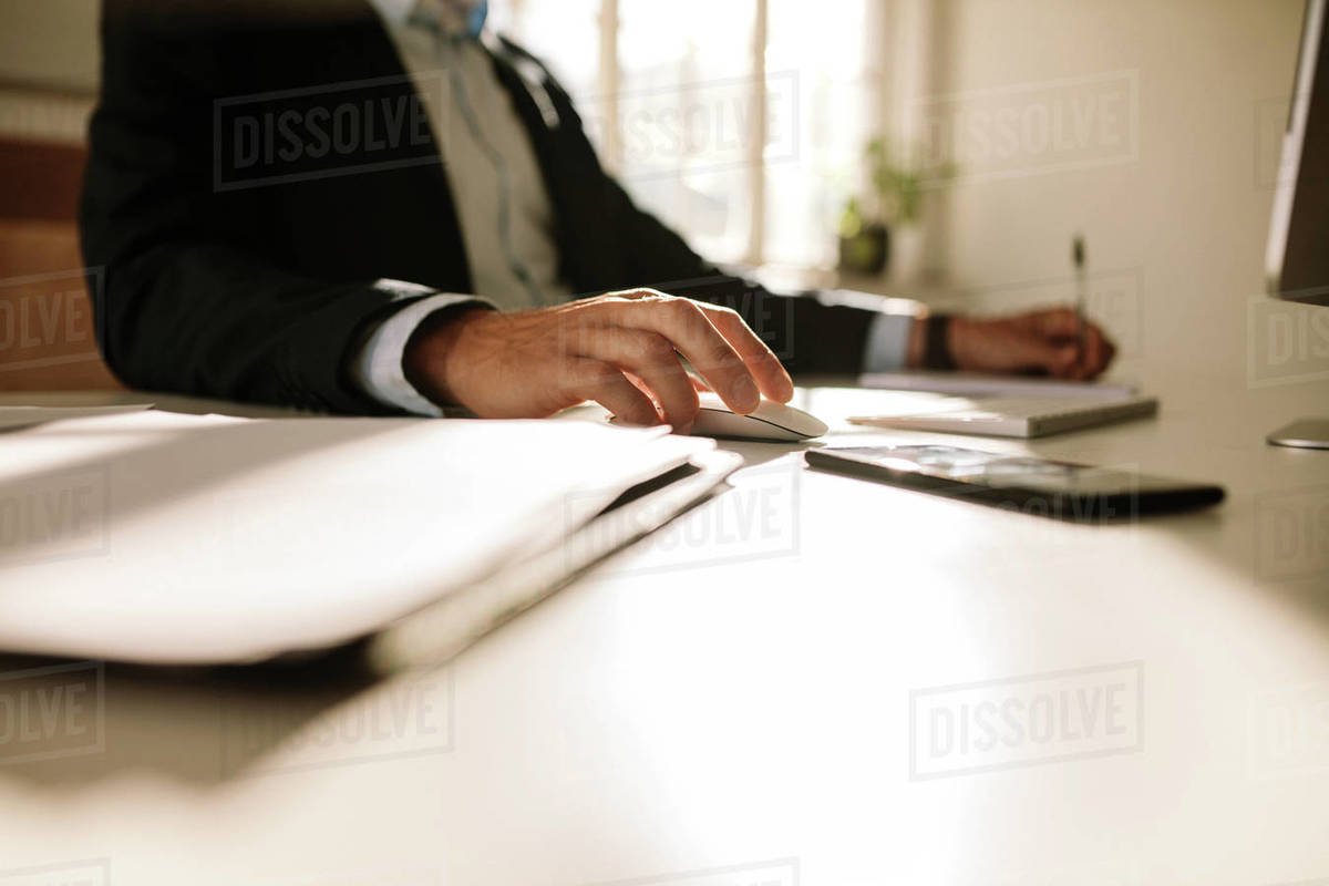 Side view of businessman operating computer sitting at his table ...