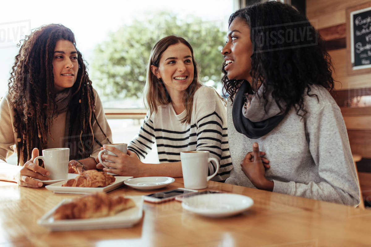 Three women sitting and talking in a restaurant. Friends sitting in a ...