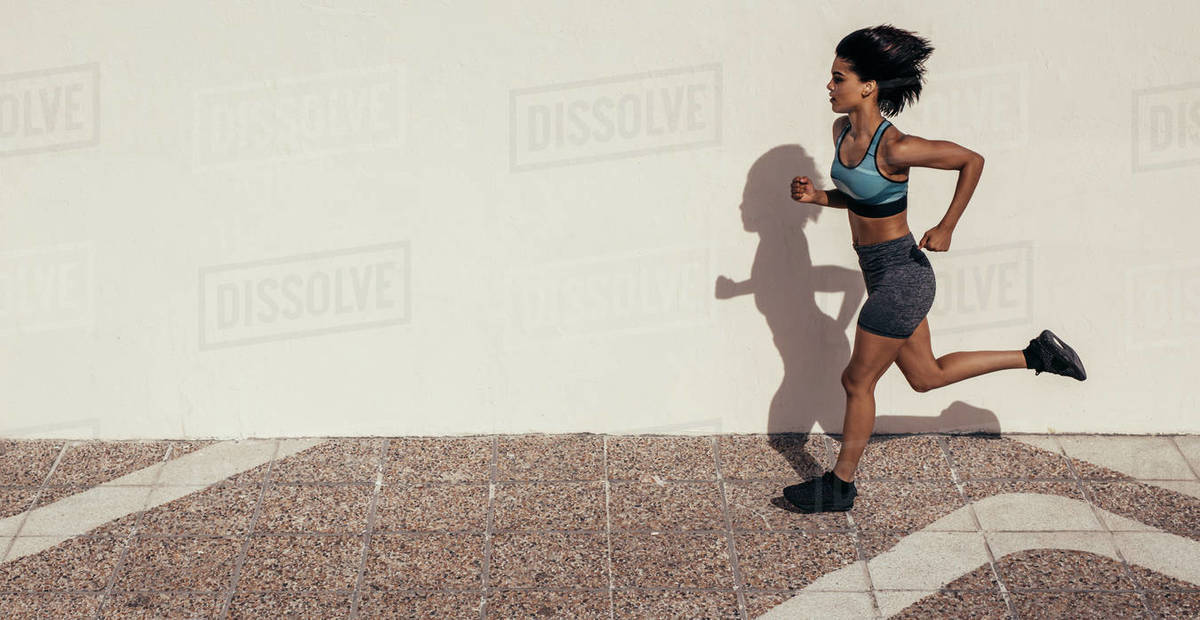 Side view shot of healthy woman athlete running outdoors. Female in ...