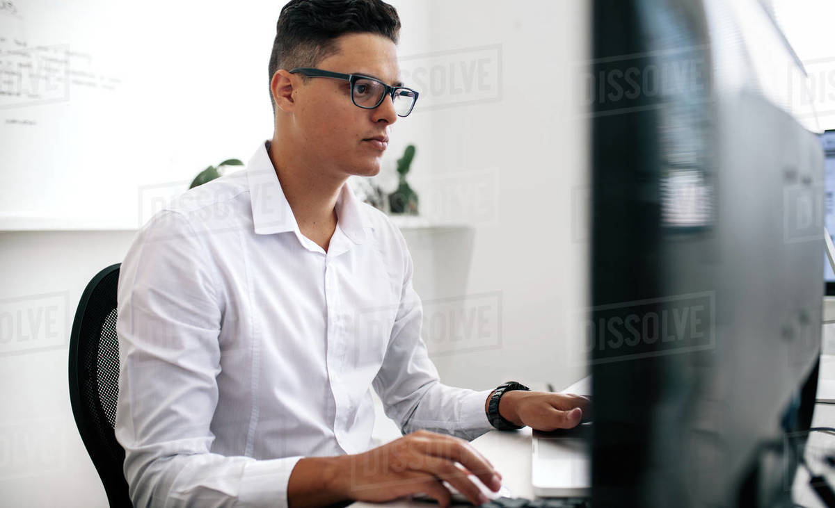 Software developer sitting in front of computer and working in office ...