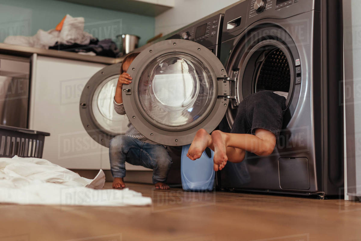 Little children playing with washing machine at home. Kids having fun ...