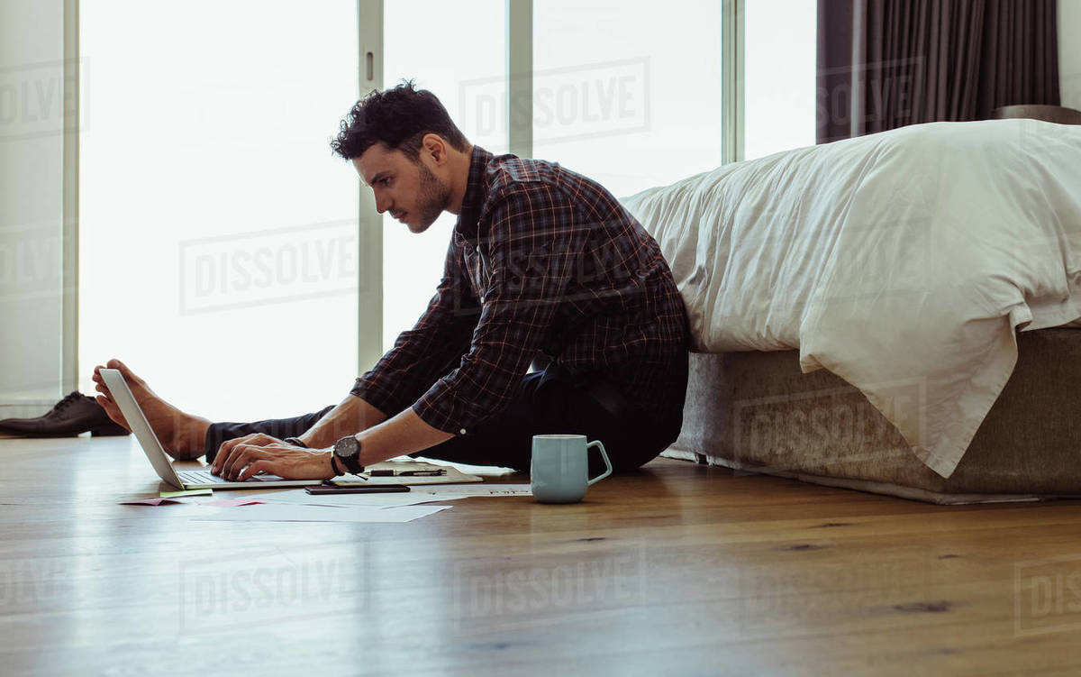 Man working on laptop computer sitting on the floor. Freelancer sitting ...
