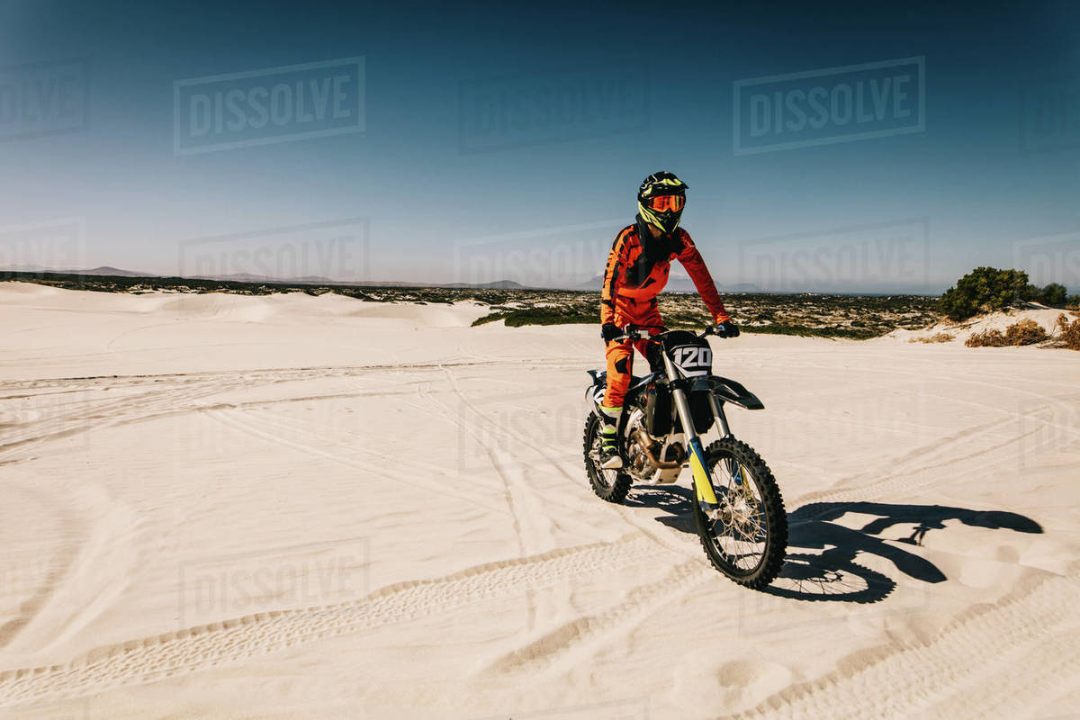 Dirt biker riding in desert. Motocross racer riding motorcycle ...