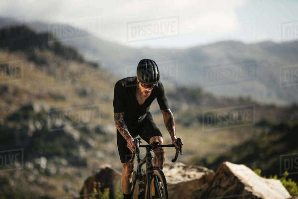 Male cyclist riding hard on pro bike on mountain road. Active sportsman ...