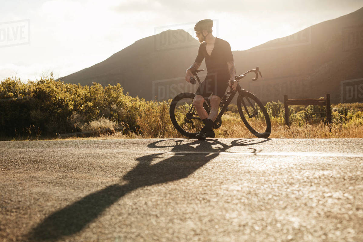 Professional male cyclist standing and leaning on his bike on ...