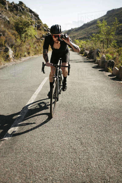 Professional cyclist riding bike and drinking water from bottle. Racer ...