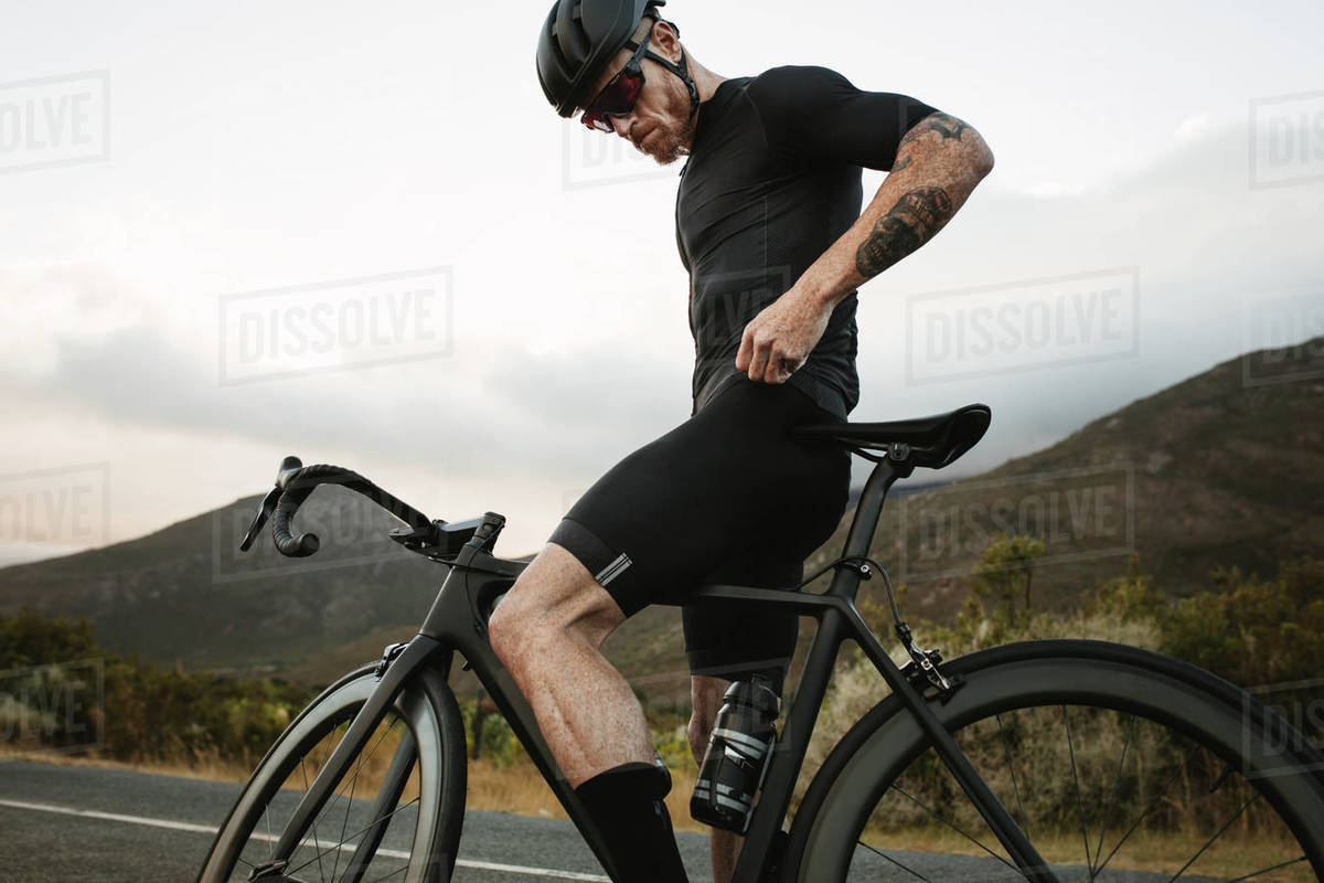 Sportsman riding bicycle and practicing outdoors on mountain highway ...