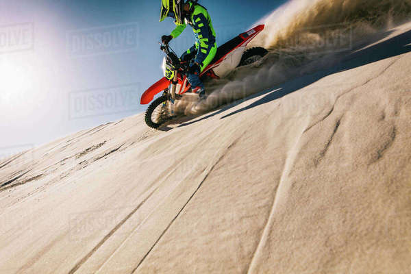 Professional motorbike rider taking a turn while riding on the sand ...