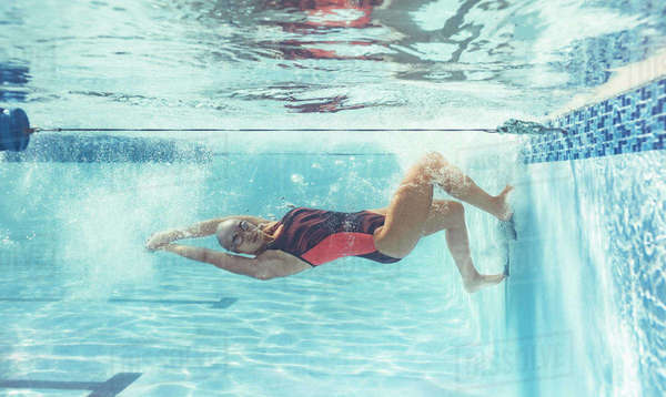 Shot of professional swimmer turning over underwater while swimming ...