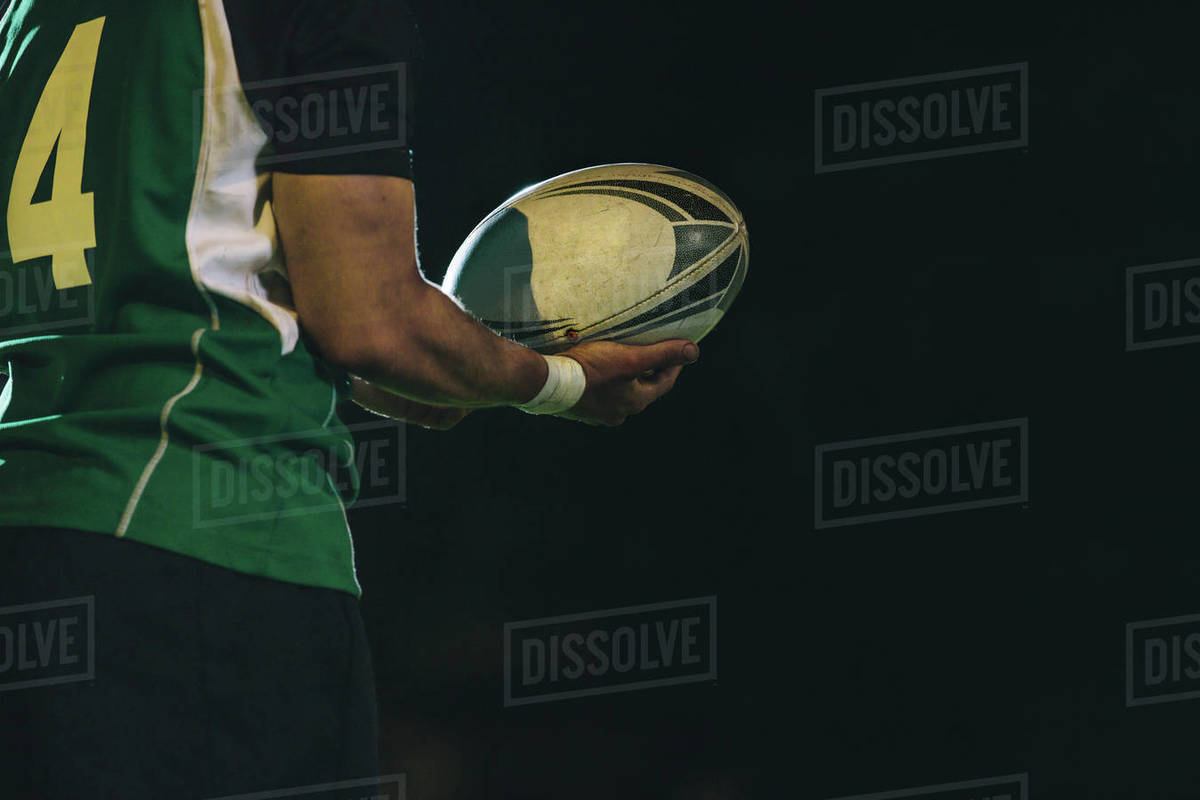 Cropped shot of professional rugby player in uniform holding a ball in ...