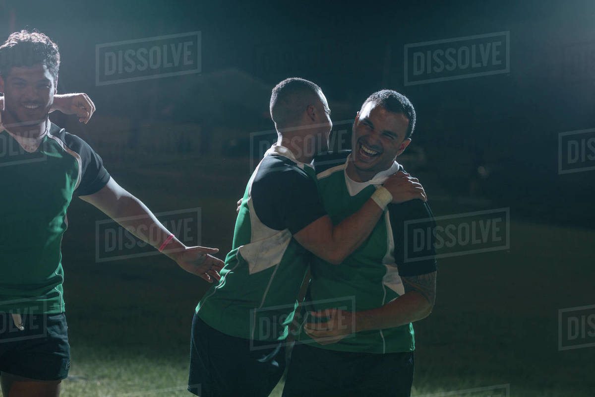 Sportsmen in uniform hugging and smiling after winning a rugby game ...