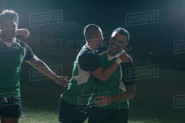 Sportsmen in uniform hugging and smiling after winning a rugby game ...