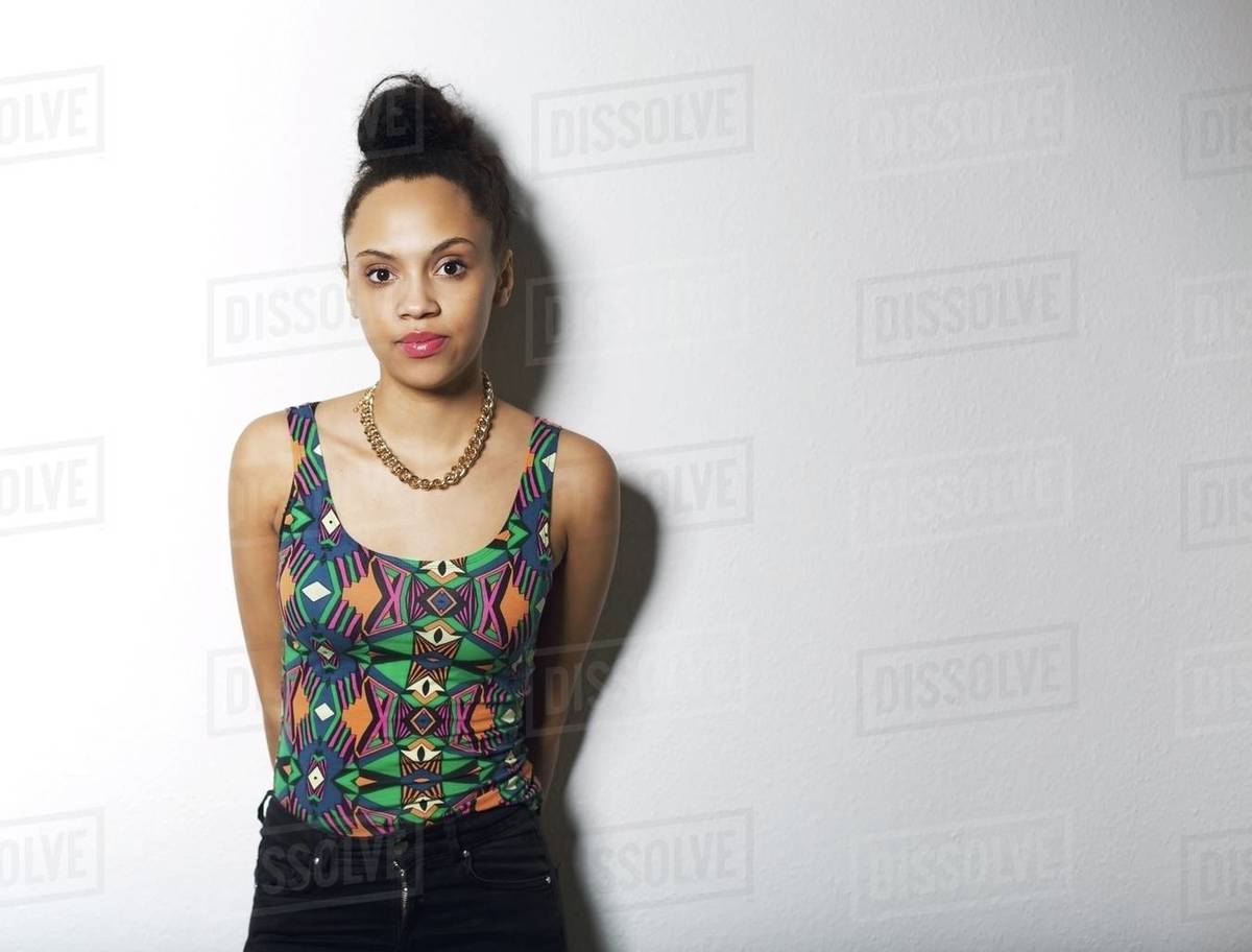 Portrait of attractive young woman standing against grey background ...