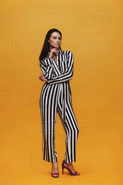 Full length portrait of female fashion model standing over orange ...