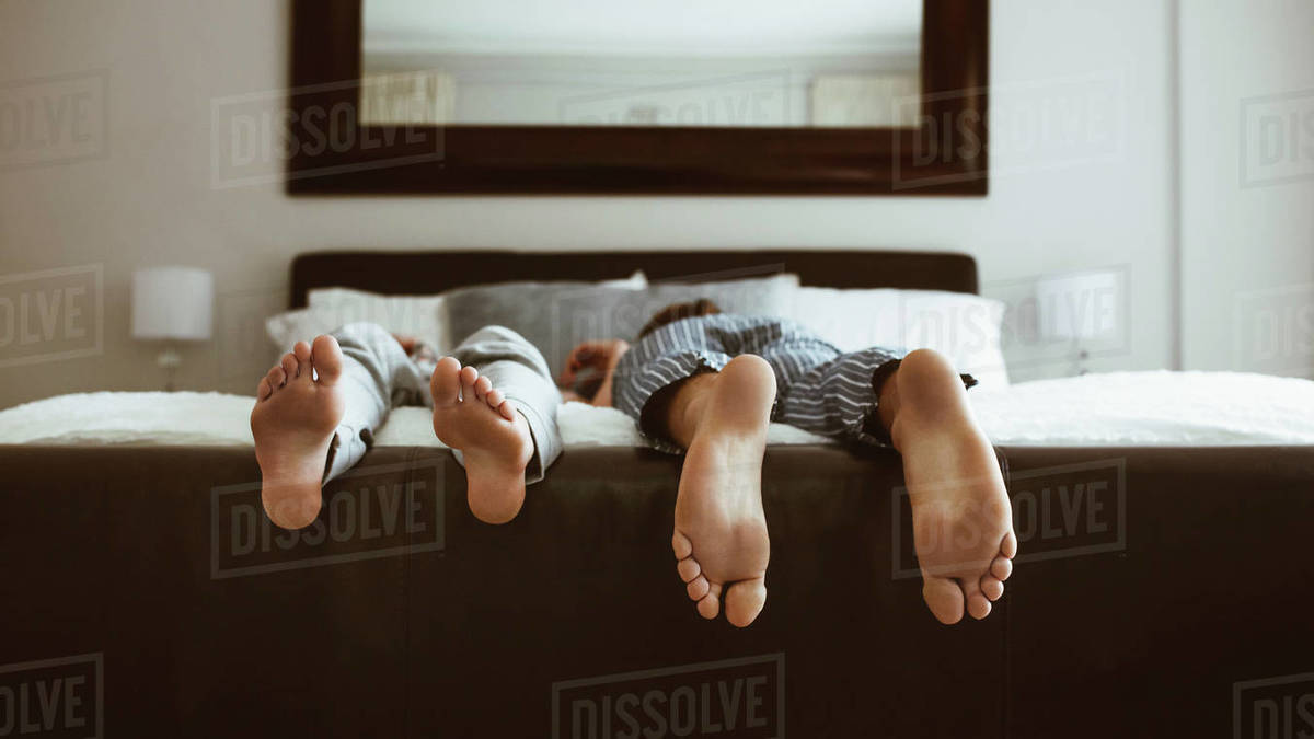 Feet of two people sleeping on bed. People sleeping on bed in different ...