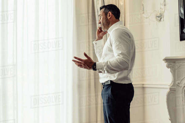 Side view of businessman talking on mobile phone while standing in ...