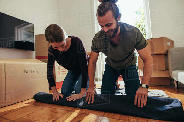 Smiling man and woman packing their household items in packing boxes ...
