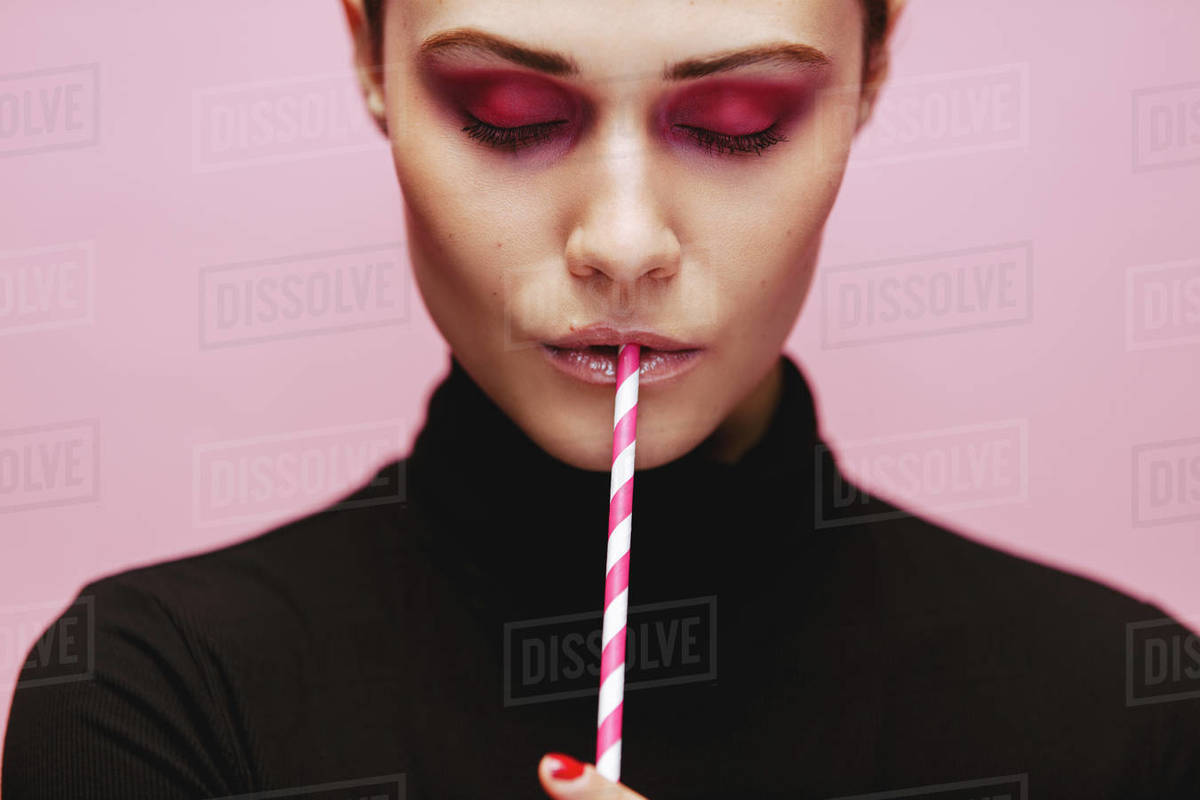 Close up of beautiful young female model with her eyes closed holding a ...