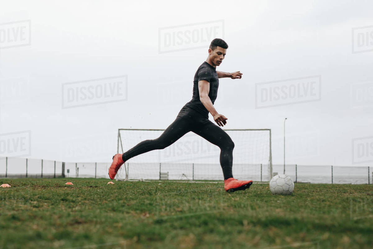 Soccer player in position to kick a football. Footballer practicing his ...