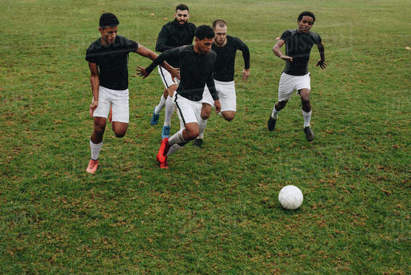 Group of men playing football on the field running for the ball. Soccer ...