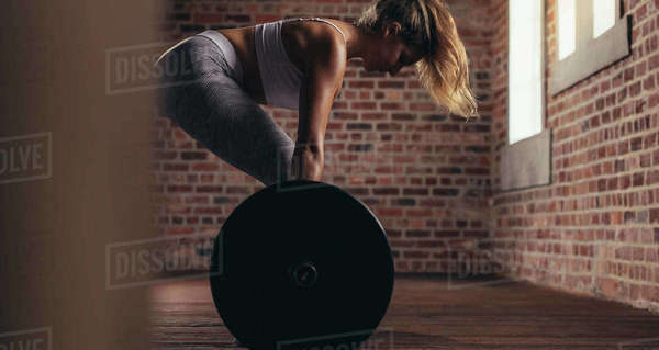 Muscular woman in gym doing heavy weight exercises. Young woman doing ...
