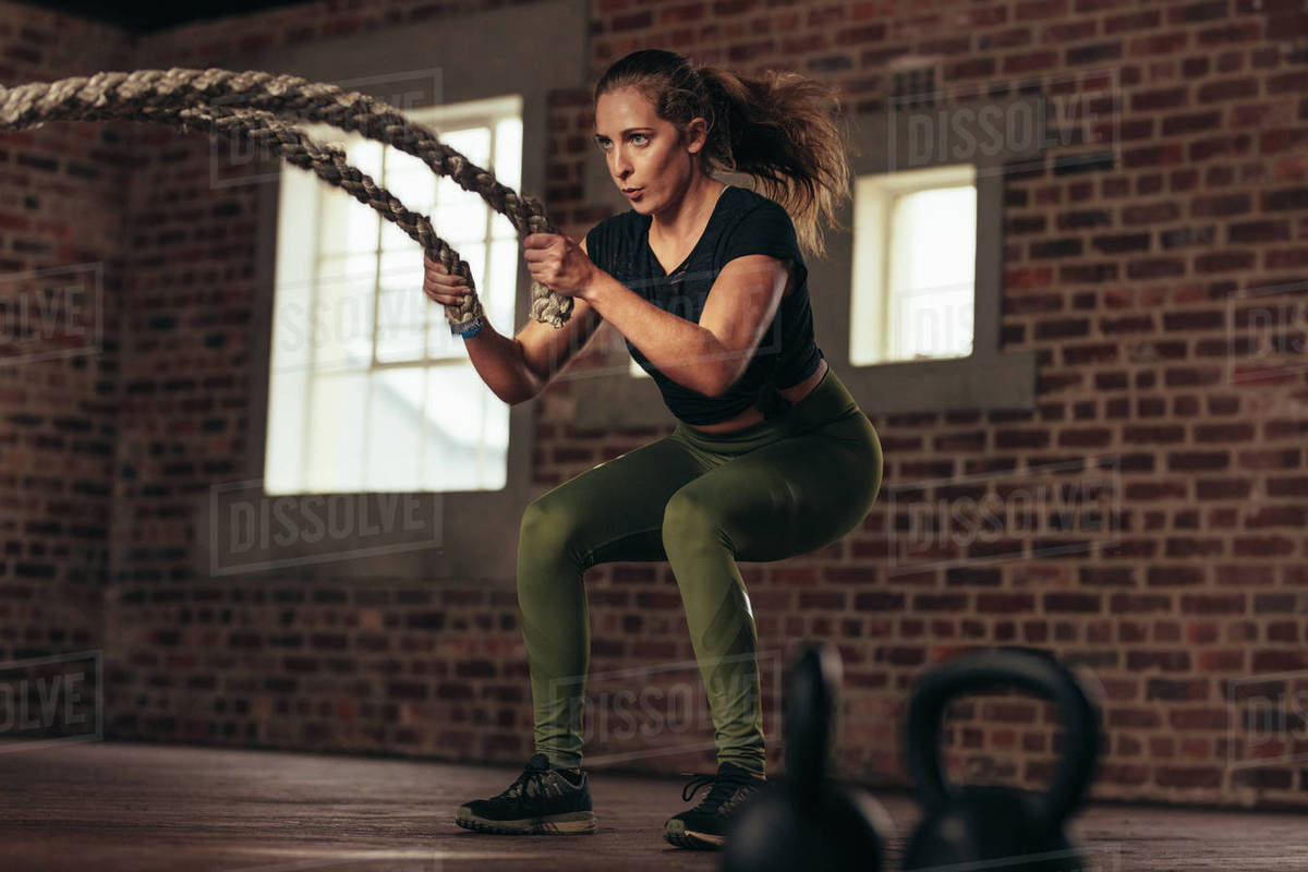 Fitness woman using battle ropes for exercising. Female working out ...