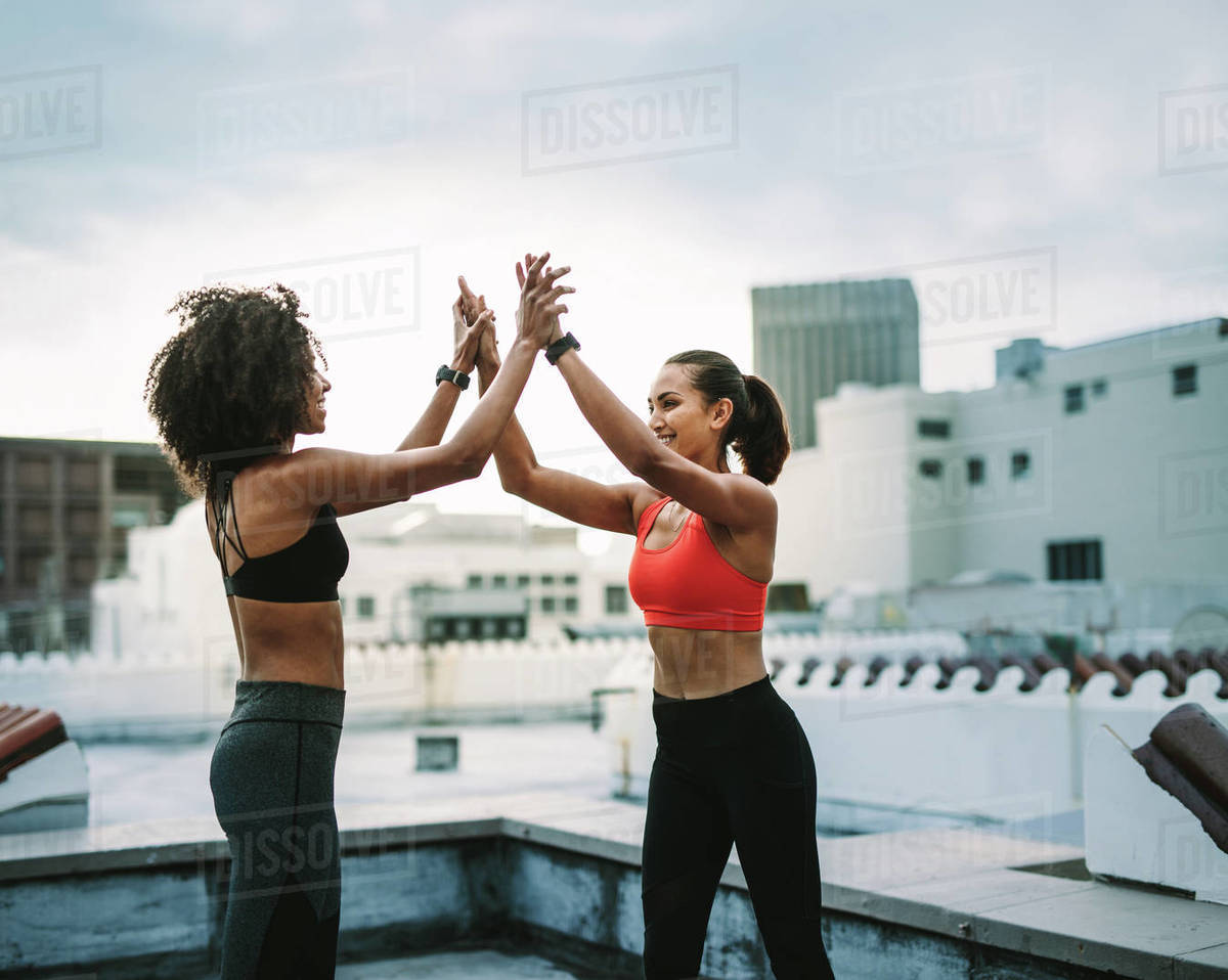 Two fitness women celebrating by giving high five after workout ...
