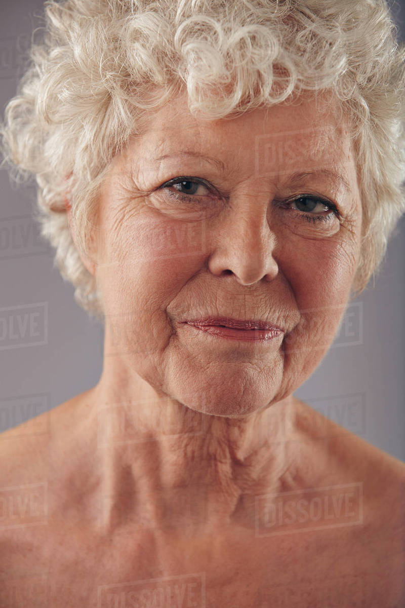 Close-up headshot of old caucasian woman face against grey background ...