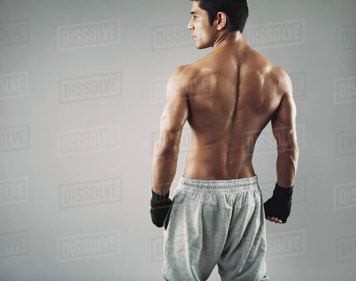 Rear view of muscular young male boxer standing looking away. Fit young ...