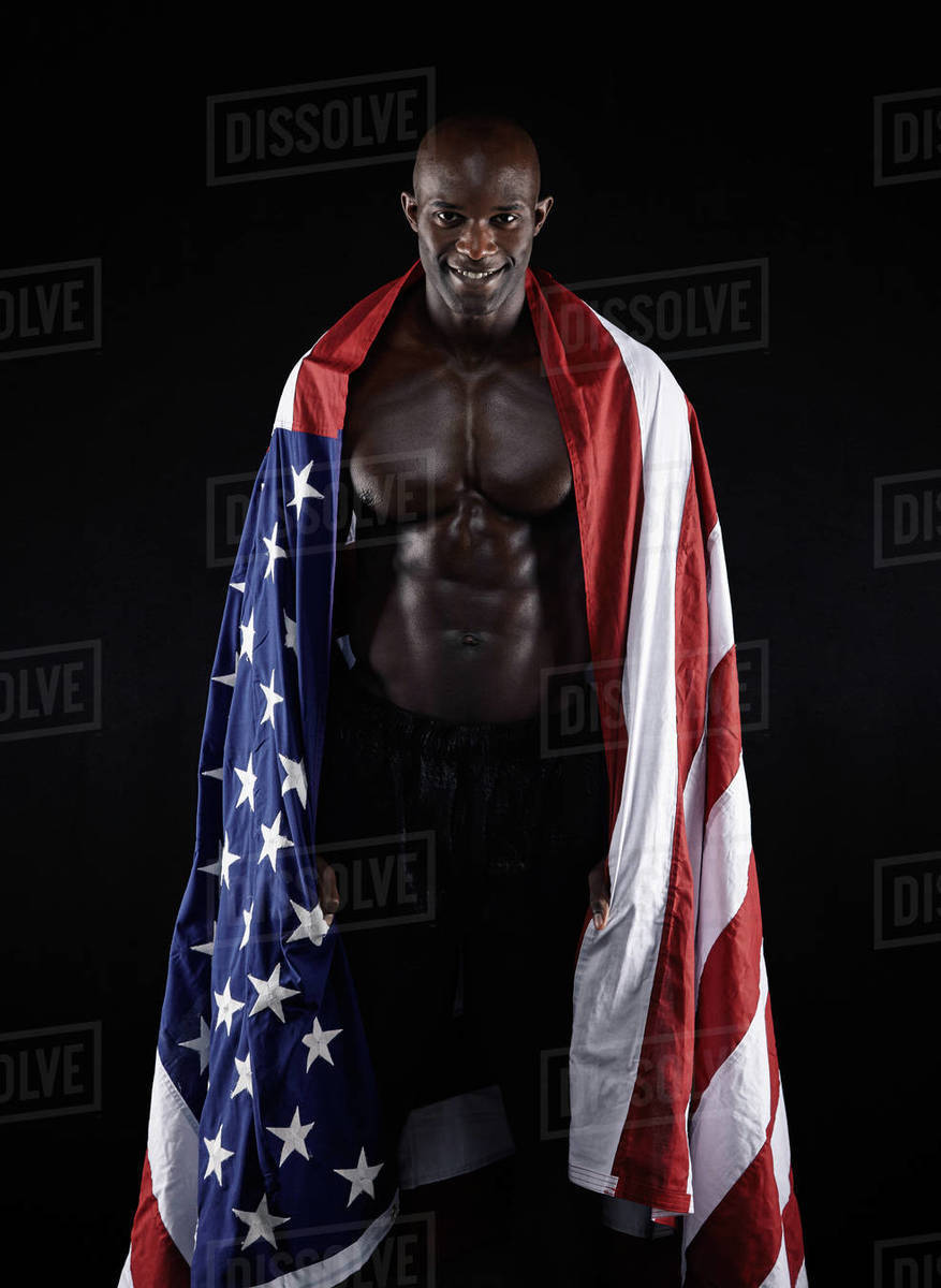 Young man wrapped in American flag against black background. Studio ...
