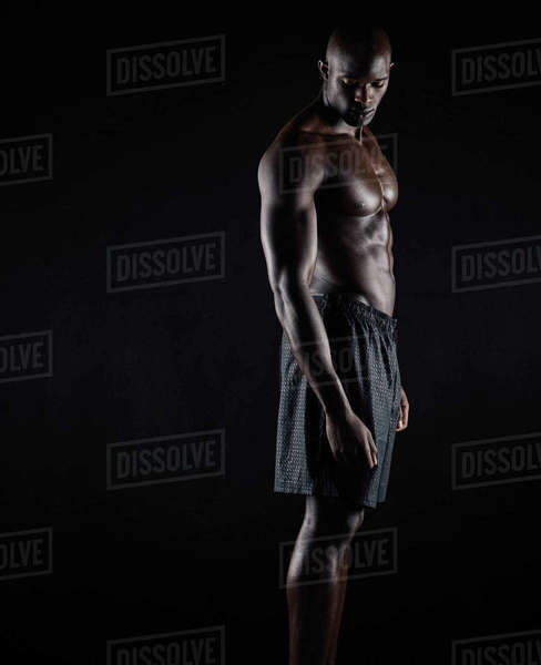 Portrait of a bodybuilder with muscular physique standing against black ...