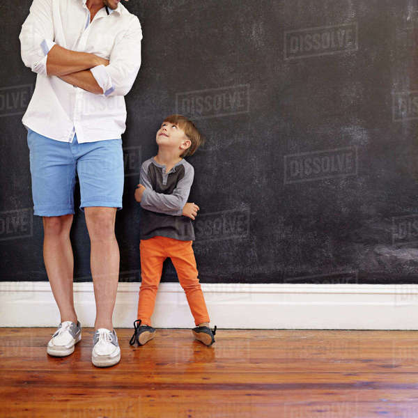 Indoor shot of little boy and his father standing with hands folded ...