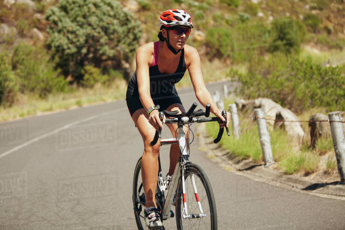Young woman triathlon athlete cycling. Caucasian female athlete riding ...