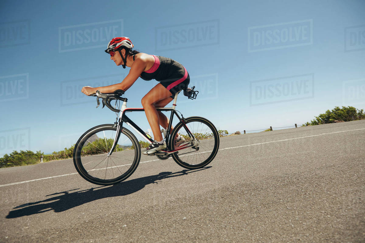 Female cyclist on a country road training for competition. Young woman ...