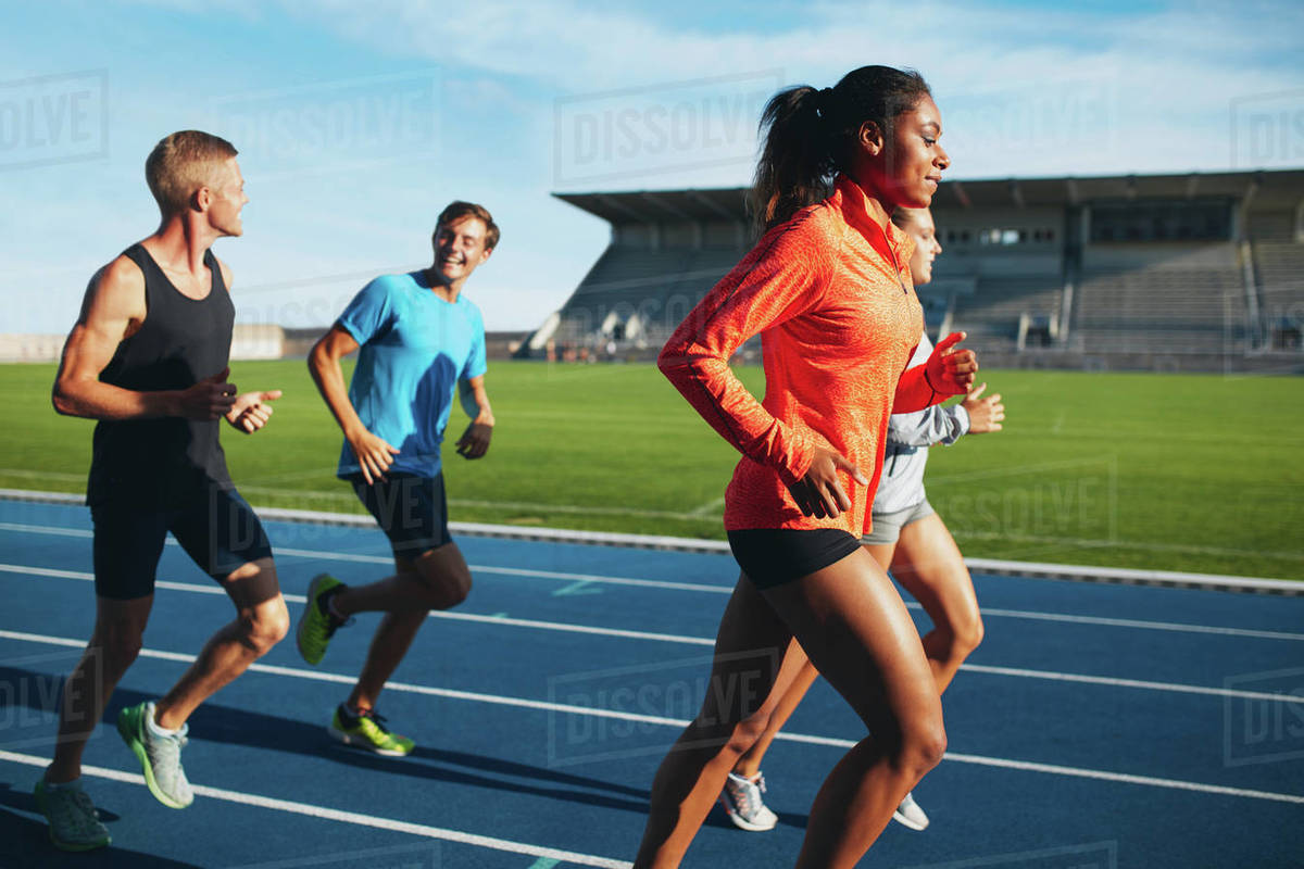 Fit men and women running on a race track. Multiracial athletes ...