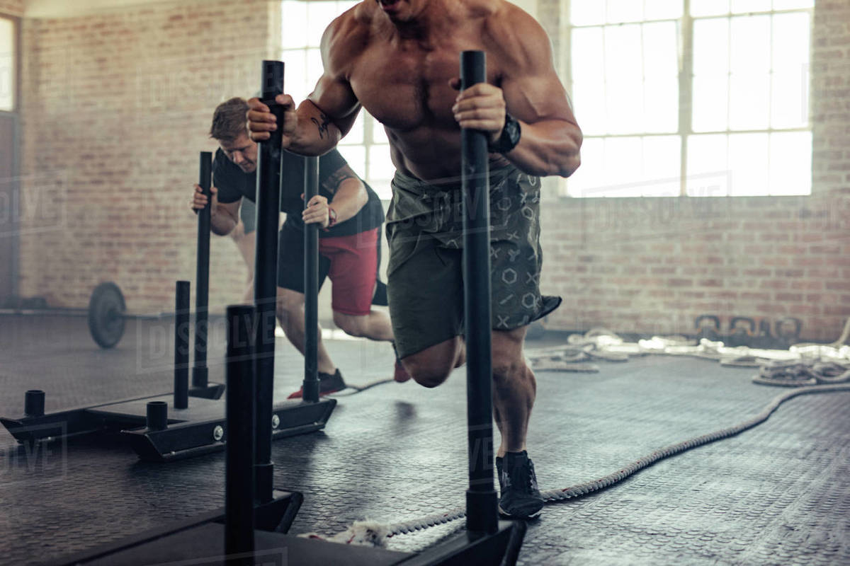 Young muscular man doing prowler sled training at crossfit gym - Stock ...