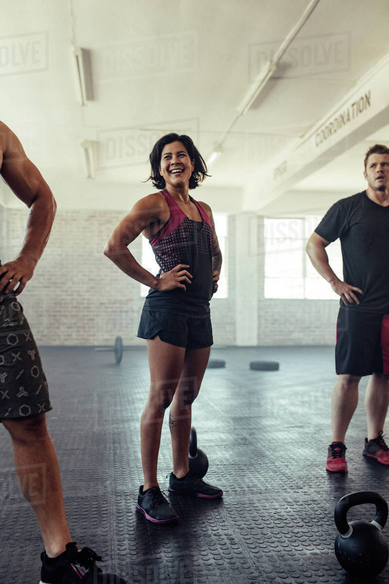Vertical image of young woman standing with friends at crossfit gym ...