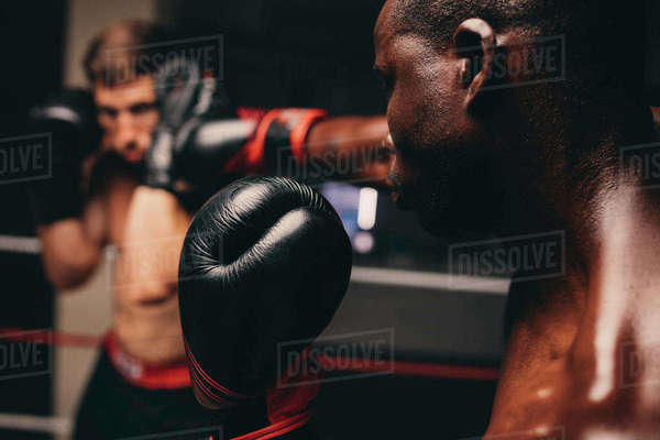 Selective focus view on face and retracted arm of boxer striking ...