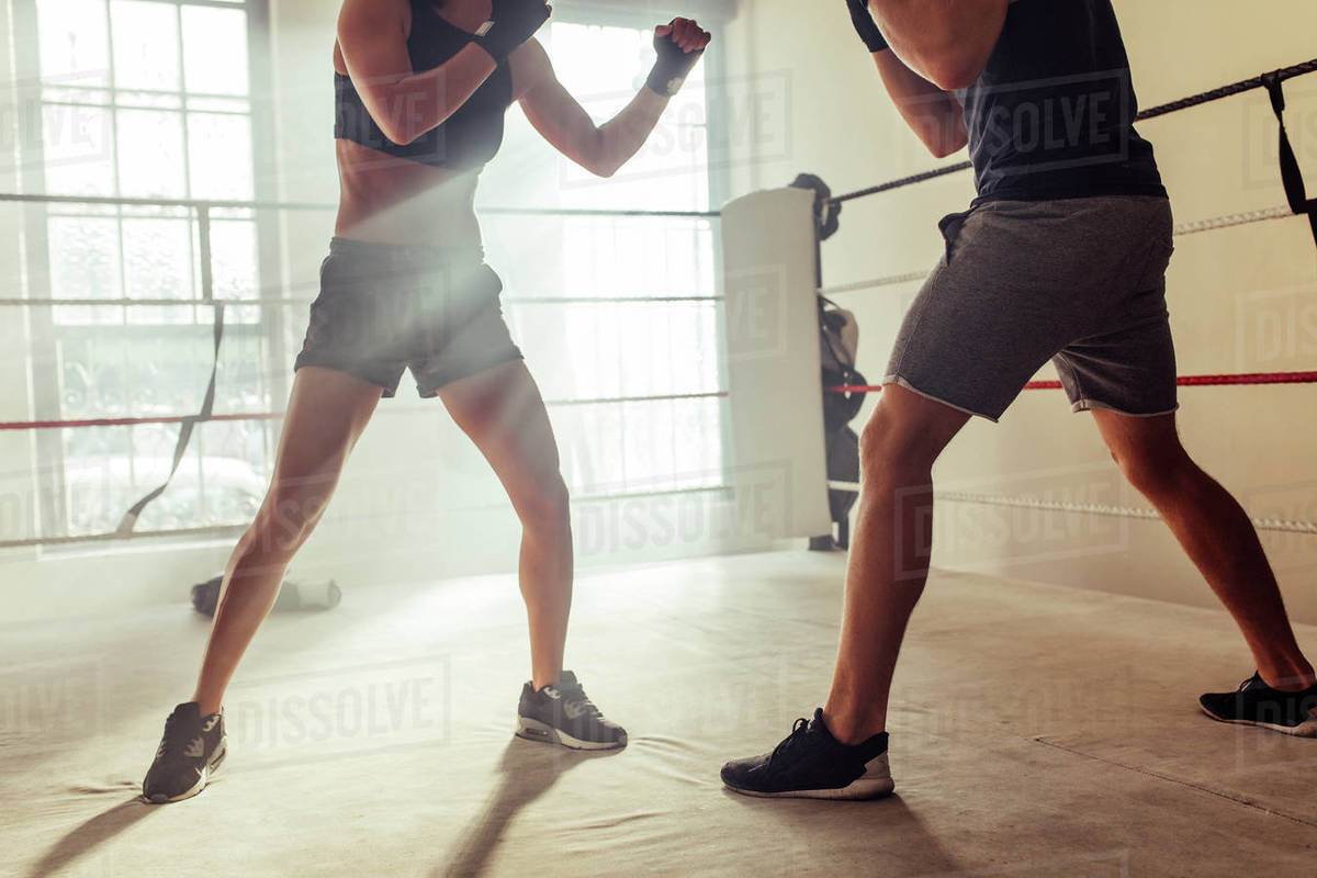 Low angle view of male and female boxers fighting in the ring besides ...