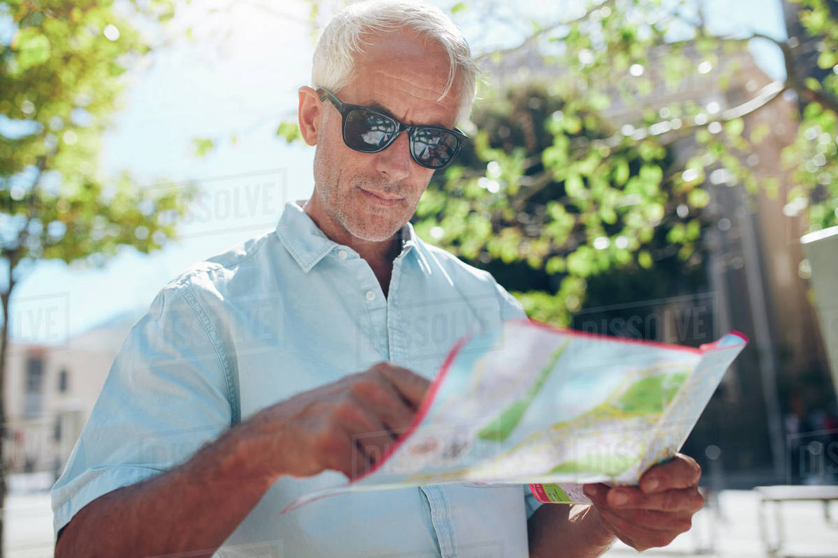 Close up shot of a senior man reading a map while standing outdoors in ...