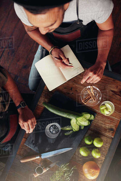 Two bartenders experimenting with creating cocktails, discussing about ...