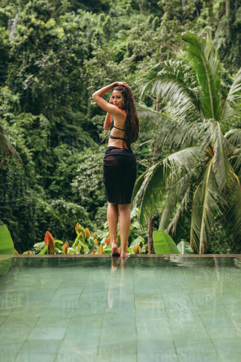 Full length portrait of beautiful bikini model posing at poolside ...